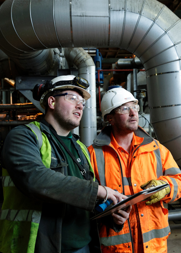 Two people holding a clipboard in high visibility jackets